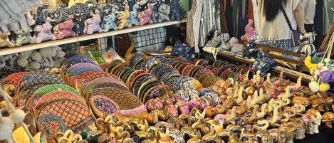 Uma banca de mercado com diversos artigos, incluindo bolsas, brinquedos de pelúcia e tecidos.