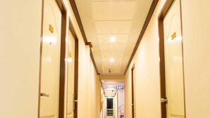 Corredor de hotel com portas em ambos os lados, piso de azulejos e sinal de saída no final.