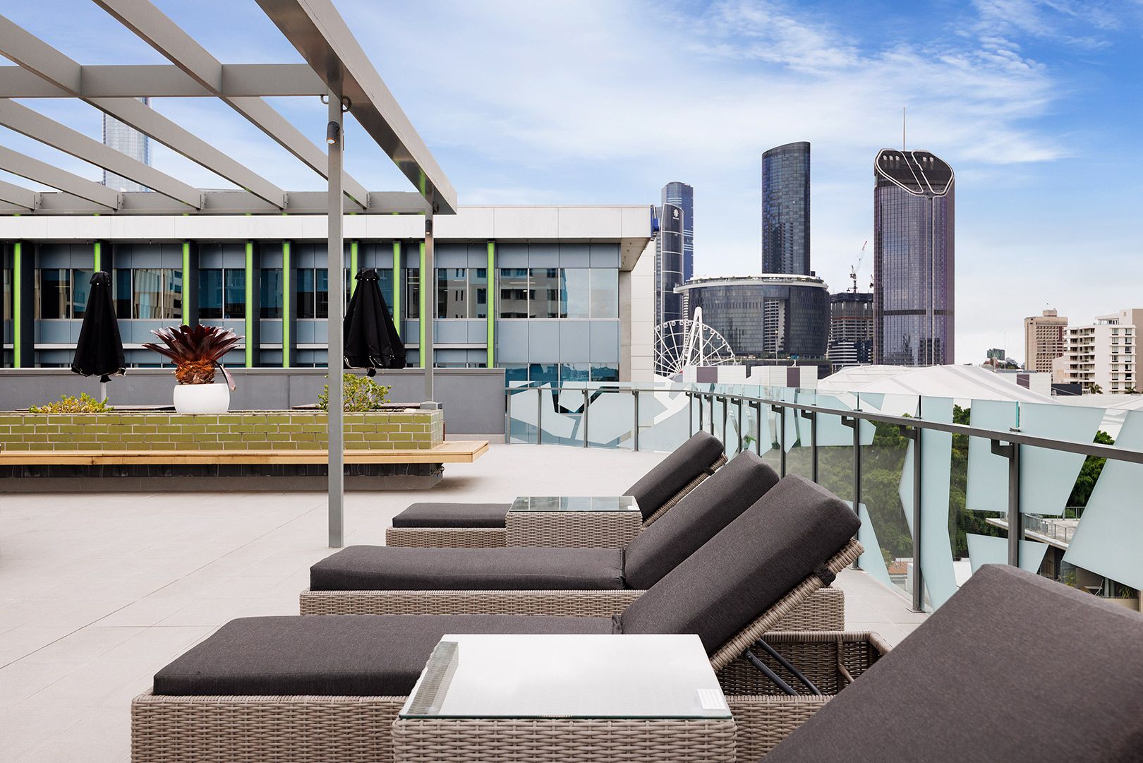 Um lounge no terraço com área externa, vista para o horizonte da cidade e edifícios modernos ao fundo.