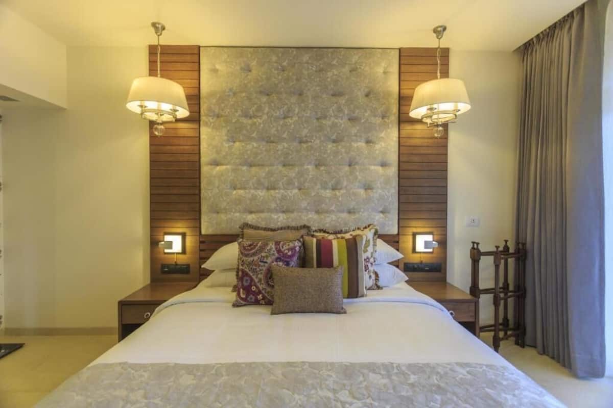Quarto com uma cama grande, duas luminárias de cabeceira, um painel de cabeceira de madeira e um criado-mudo com abajur.