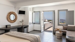 Quarto moderno com cama, escrivaninha, televisão e varanda com vista.