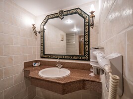 Casa de banho com um espelho grande, lavatório e aquecedor de toalhas.
