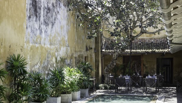 Um pátio com piscina, plantas em vasos e área de estar externa.