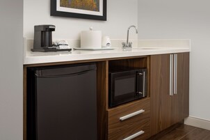 Cozinha compacta com cafeteira, micro-ondas e pia.