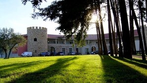 Um edifício de pedra com uma torre, rodeado de árvores e carros estacionados.