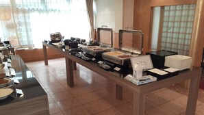 Uma mesa com buffet, diversos alimentos e utensílios de servir.