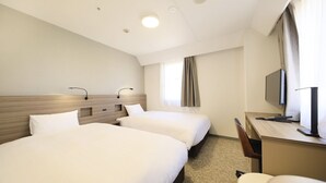 Quarto de hotel com duas camas, uma escrivaninha, uma cadeira, uma televisão e uma janela com cortinas.