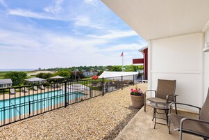 Uma varanda com piscina, uma cadeira e vista para a paisagem.