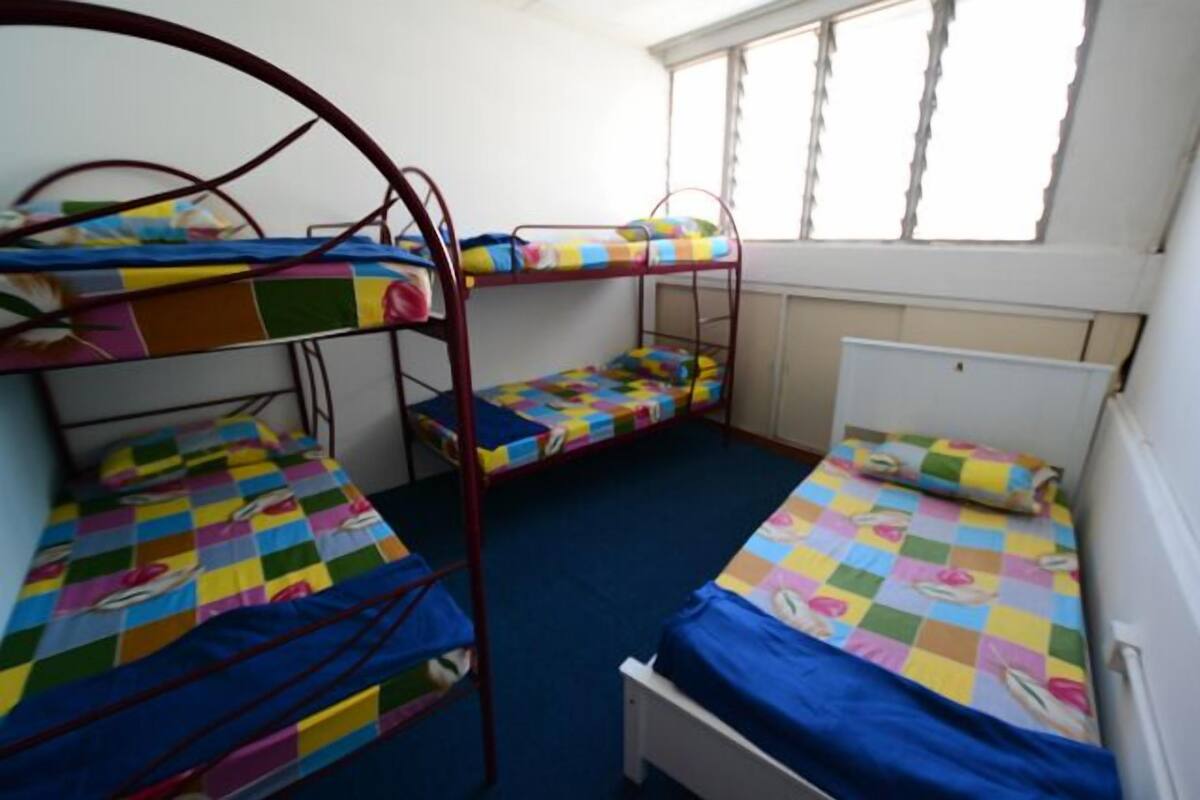 Um quarto de dormitório com beliches, uma janela com persianas e um radiador.