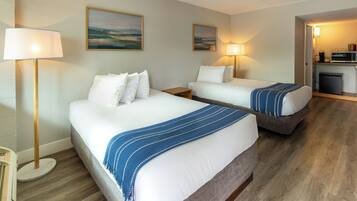Quarto de hotel com duas camas, uma pequena cozinha e vista para o exterior.