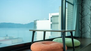 Quarto moderno com vista para a água e edifícios no horizonte.