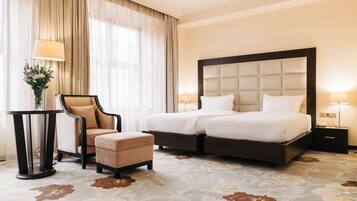 Quarto de hotel com uma cama grande, uma cadeira, uma mesa pequena e um abajur.
