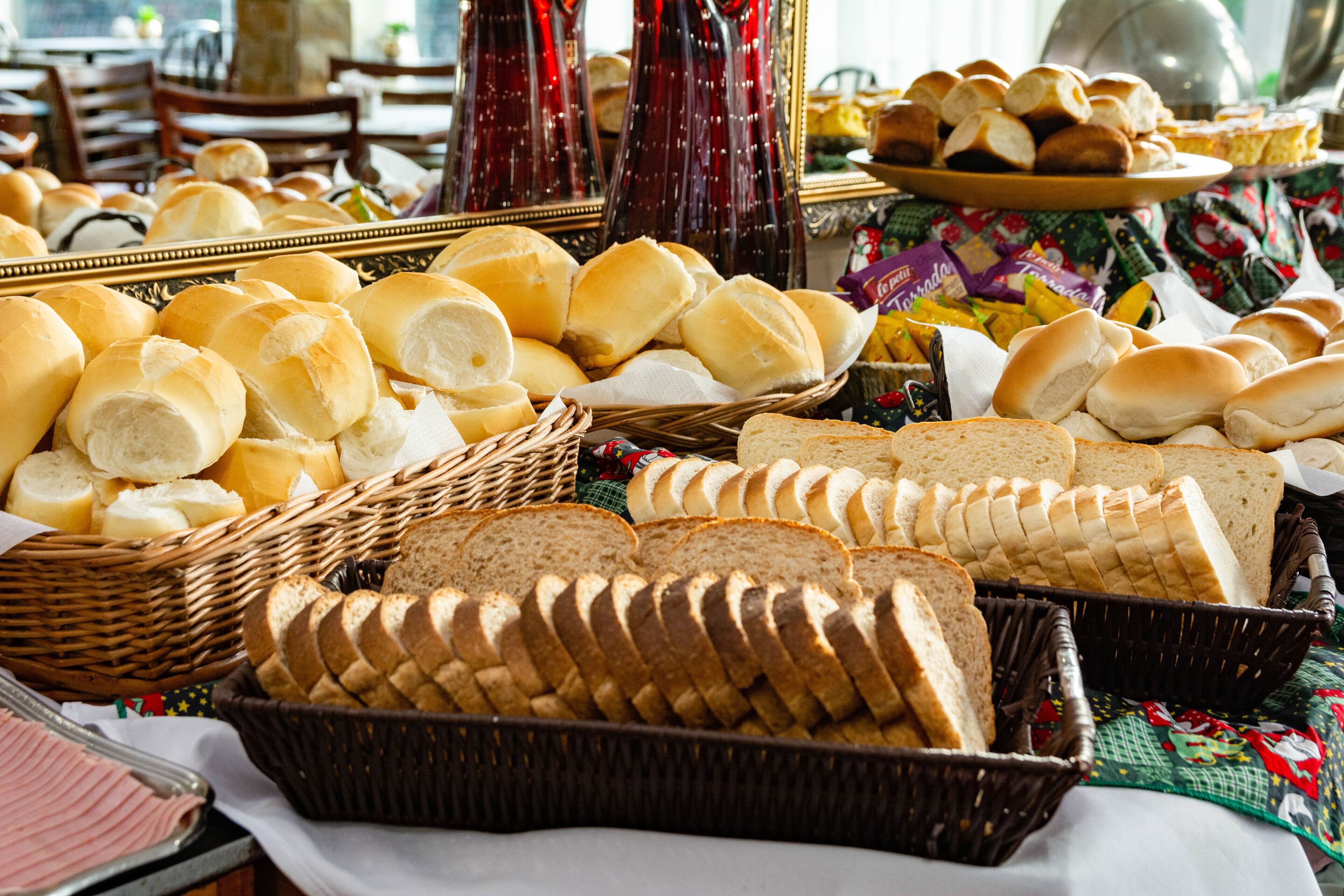 Diversos pães e doces dispostos sobre uma mesa.
