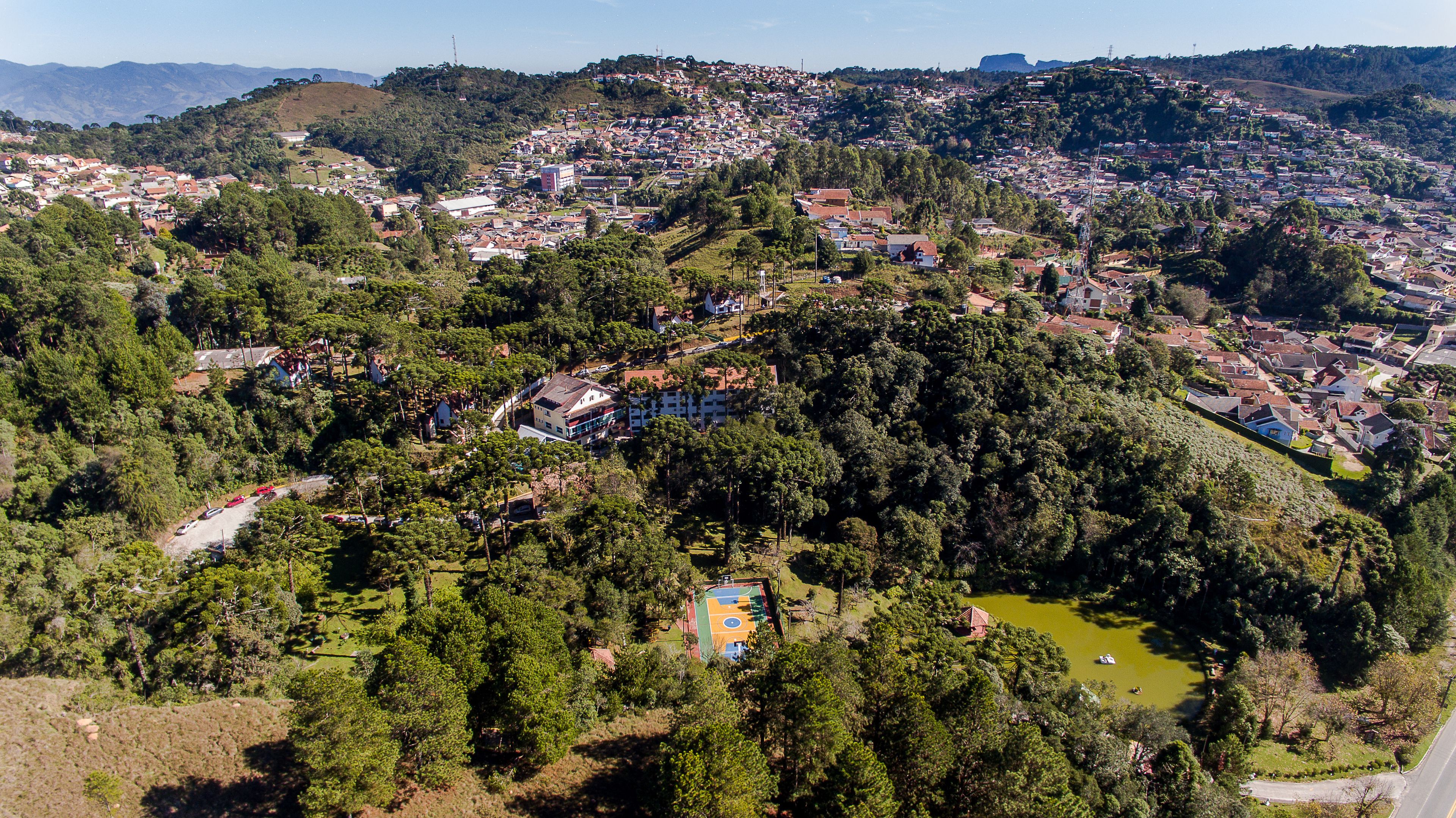 Vista aérea de uma área residencial com casas, quadra de basquete e um pequeno lago.