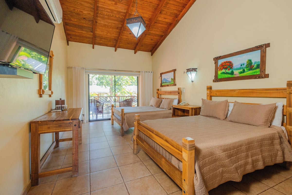 Um quarto com cama de madeira, uma escrivaninha de madeira, uma televisão e um quadro na parede.