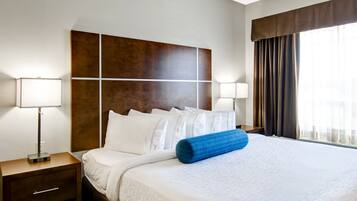 Quarto de hotel com uma cama grande, duas mesas de cabeceira e um encosto de cama.