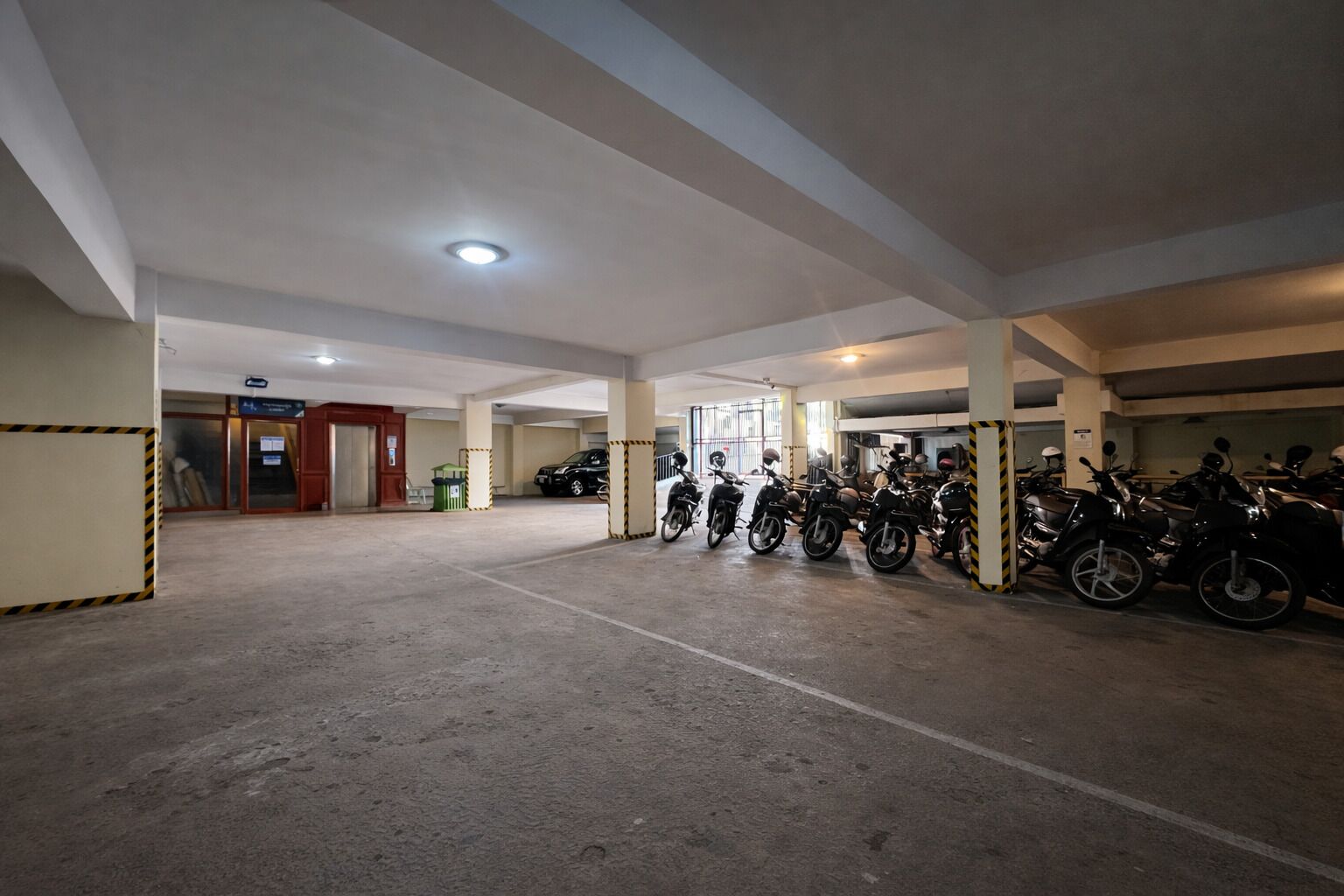 Um estacionamento com várias motocicletas estacionadas em fileiras.
