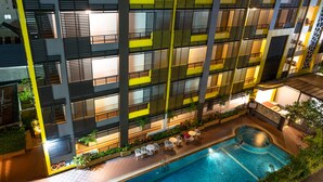 Um hotel com vários andares, varandas, piscina e área de estar ao ar livre.