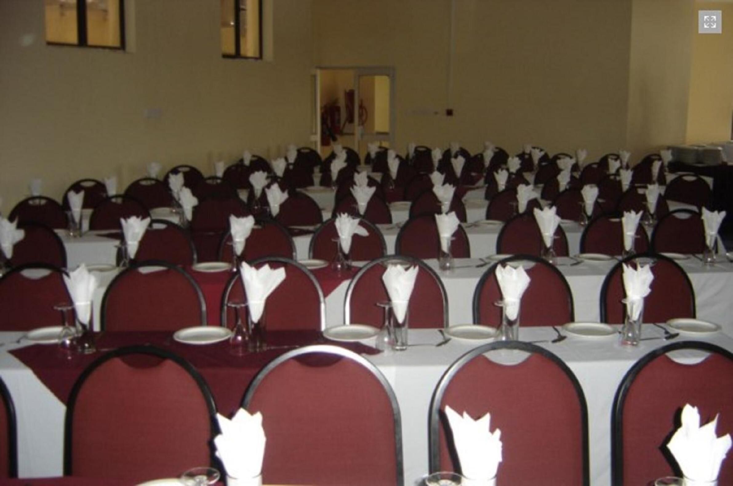 Uma sala de conferência com fileiras de mesas preparadas para uma reunião.