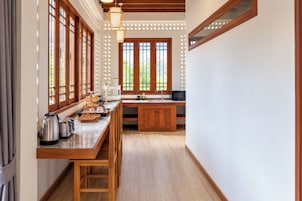 Cozinha com armários de madeira, bancada de mármore e vista para o verde lá fora.