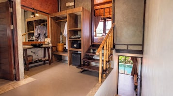 Interior em madeira com cozinha, escada e vista para uma piscina.