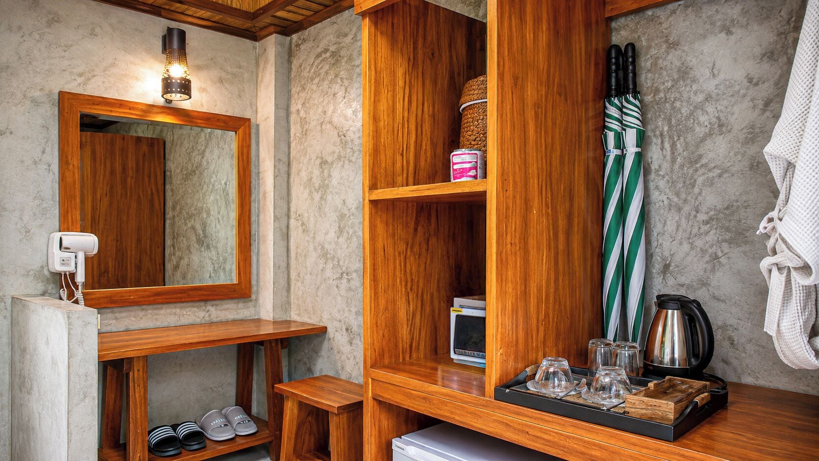 Casa de banho com prateleiras de madeira, espelho, secador de cabelo, chaleira e porta-toalhas.