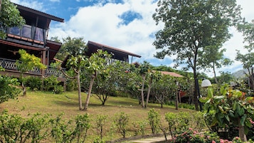 Área residencial com uma casa, varanda e muita vegetação e árvores.