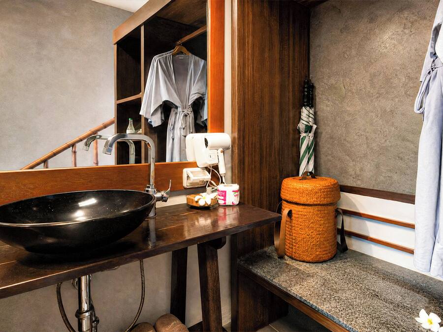 Casa de banho com lavatório preto, dispensador de toalhas e cesta de vime no balcão.
