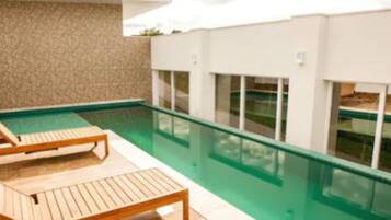Uma piscina com duas espreguiçadeiras e um deck revestido.