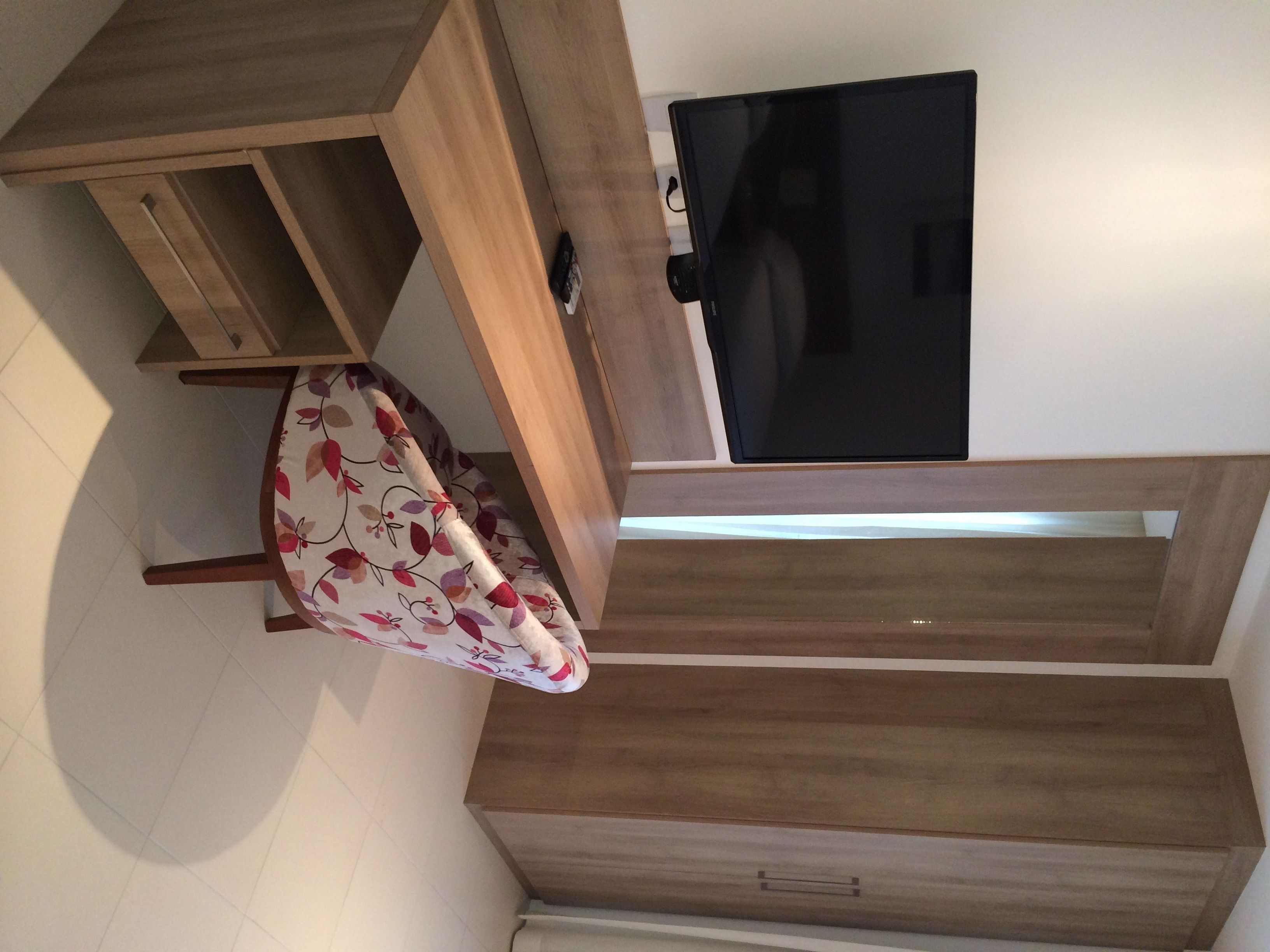 Uma sala de estar moderna com um painel de TV de madeira, uma televisão de tela plana e uma poltrona estampada com flores.