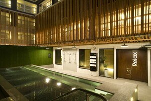 Uma área de piscina coberta moderna, com barreira de vidro, painéis de madeira e uma placa com a palavra 'Relax'.