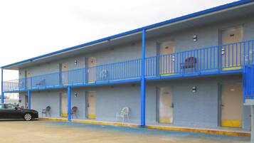 Um motel com fachada azul, várias divisões e um carro estacionado em frente.