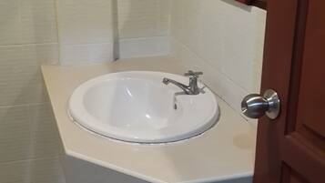 Casa de banho com lavatório branco, espelho e porta.