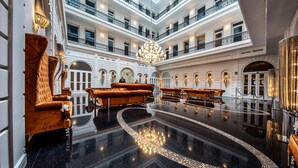 Um hall de hotel luxuoso com uma piscina refletora central, assentos elegantes e um lustre imponente.