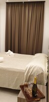 Quarto de hotel com uma cama, um serviço de bandeja com uma garrafa de champanhe e um conjunto de toalhas.