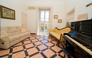 Uma sala de estar com um sofá bege, um sofá amarelo, um piano preto e um chão quadriculado.