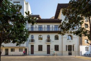 Um edifício com fachada simétrica, várias janelas e uma varanda.