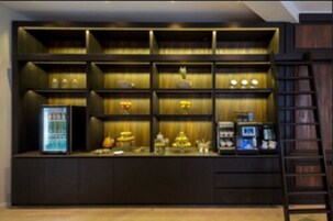 Uma estante de madeira escura com vários compartimentos, alguns contendo objetos decorativos e outros, dispositivos eletrônicos.