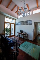 Um quarto espaçoso com escada de madeira, um lustre, uma mesa com computador e uma grande janela.
