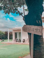 Placa indicando sauna e spa, uma árvore e um edifício com área externa para sentar.