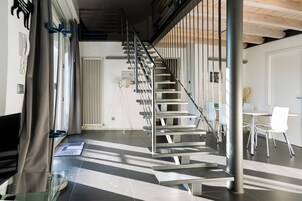 Um interior moderno com uma escada, uma mesa de vidro e uma cadeira branca.