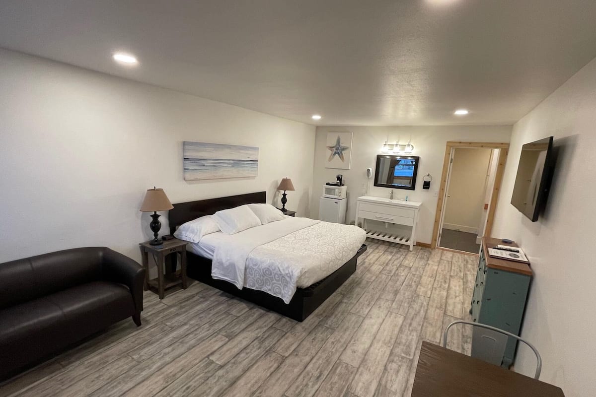 Quarto com cama, mesas de cabeceira, televisão e escrivaninha.