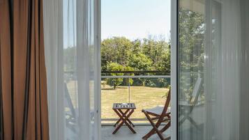 Uma varanda com mesa e cadeiras, vista para um gramado e árvores.