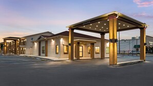 Entrada de um hotel com área de espera coberta, estacionamento e uma loja Starbucks ao fundo.