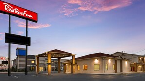 Red Roof Inn com área de estacionamento coberta e céu claro.