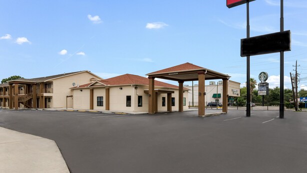 Um Red Roof Inn com um prédio de dois andares, área de estacionamento coberta e um drive-thru da Starbucks.