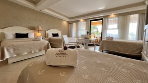Quarto de hotel com duas camas, uma mesa de jantar e um pequeno espaço de estar.