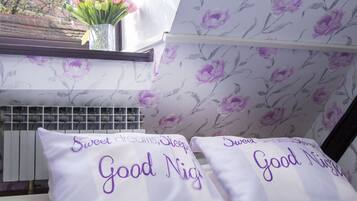 Quarto com papel de parede floral, janela com vista para árvores e almofadas com a inscrição 'Sweet Dreams, Sweet Sleep'.