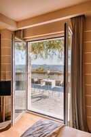 Quarto com uma grande porta de correr de vidro que dá para um terraço ao ar livre com mesa e cadeiras.