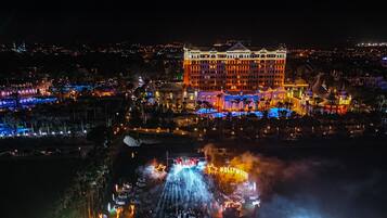 Um hotel com um edifício grande e uma área de piscina iluminada.